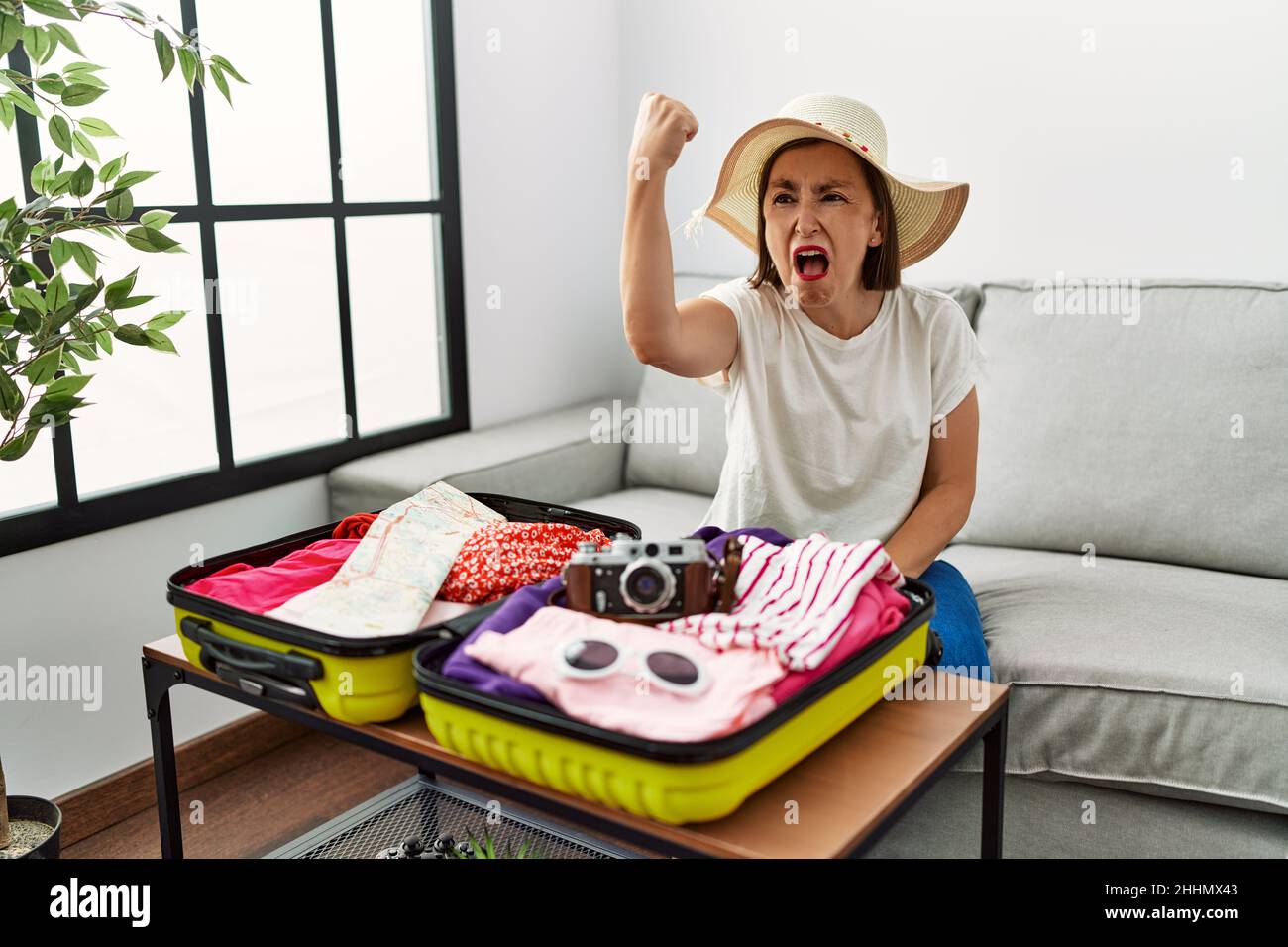 Beautiful middle age hispanic woman packing summer clothes in suitcase ...