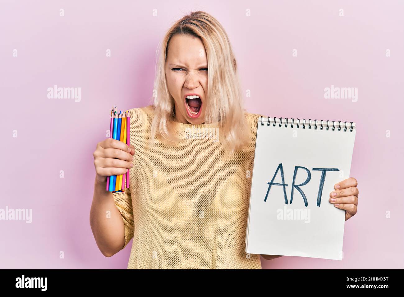 Beautiful caucasian blonde woman holding art notebook and color pencils ...
