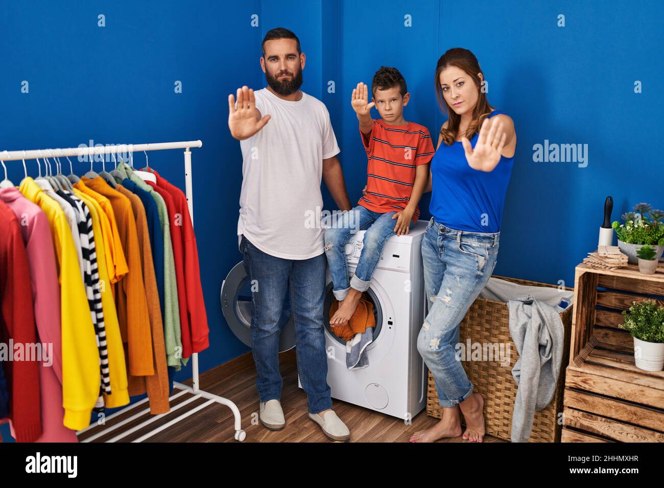Family of three at laundry room with open hand doing stop sign with ...