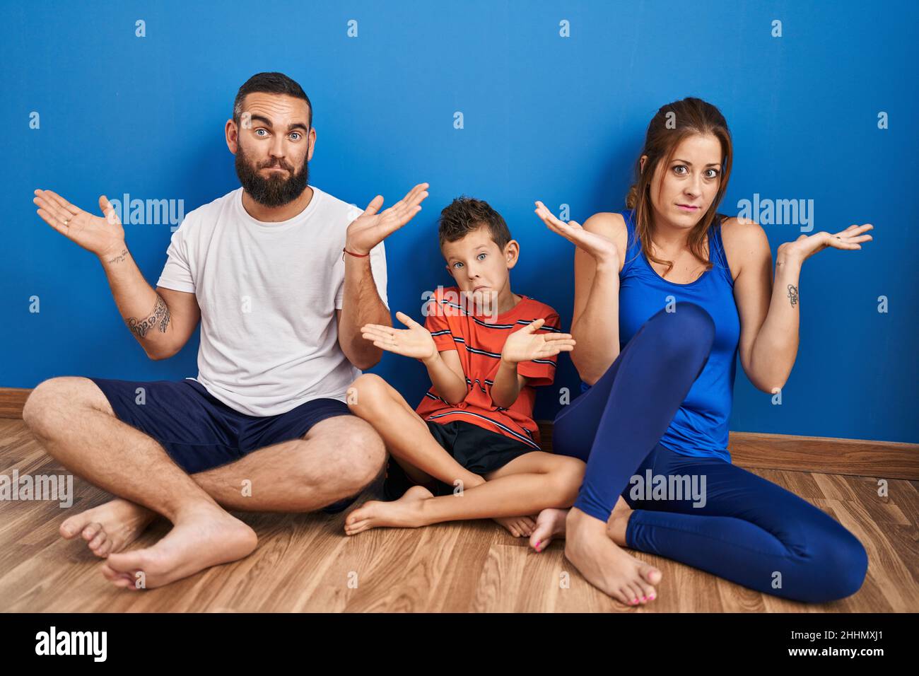 Family of three sitting on the floor at home clueless and confused ...