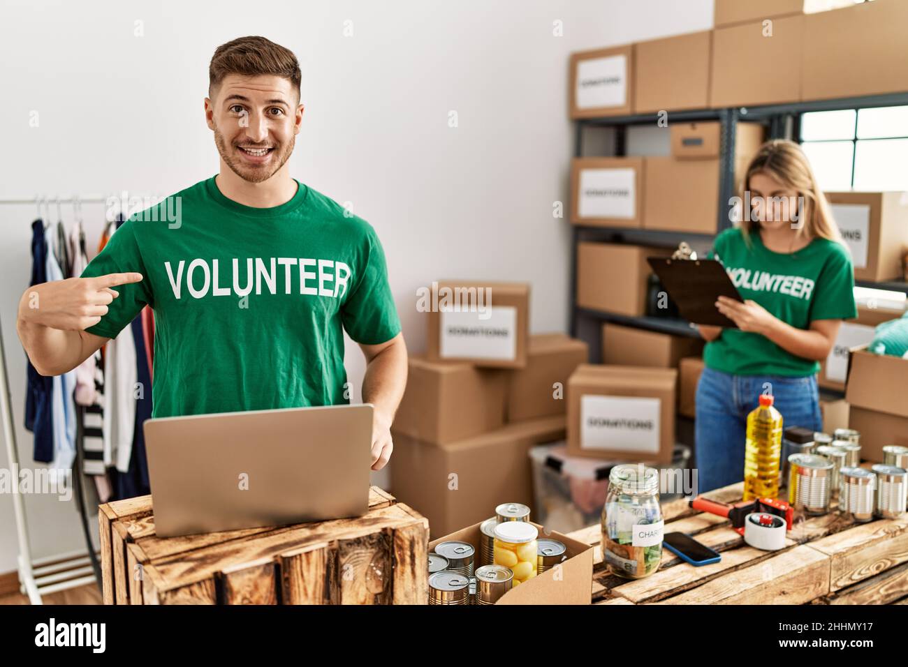 Young man and woman wearing volunteer t shirt at donations stand ...