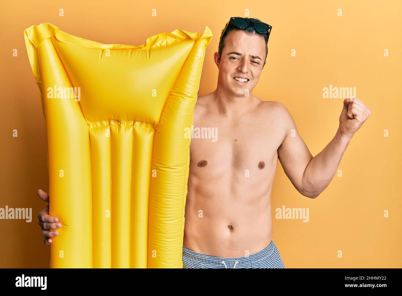 Handsome young man wearing swimsuit and holding summer float screaming ...