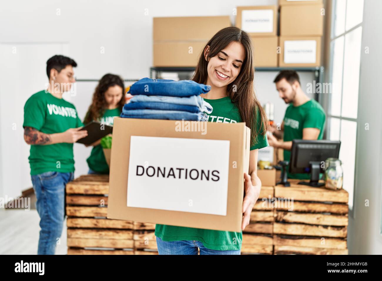 Group of young volunteers working at charity center. Woman smiling ...