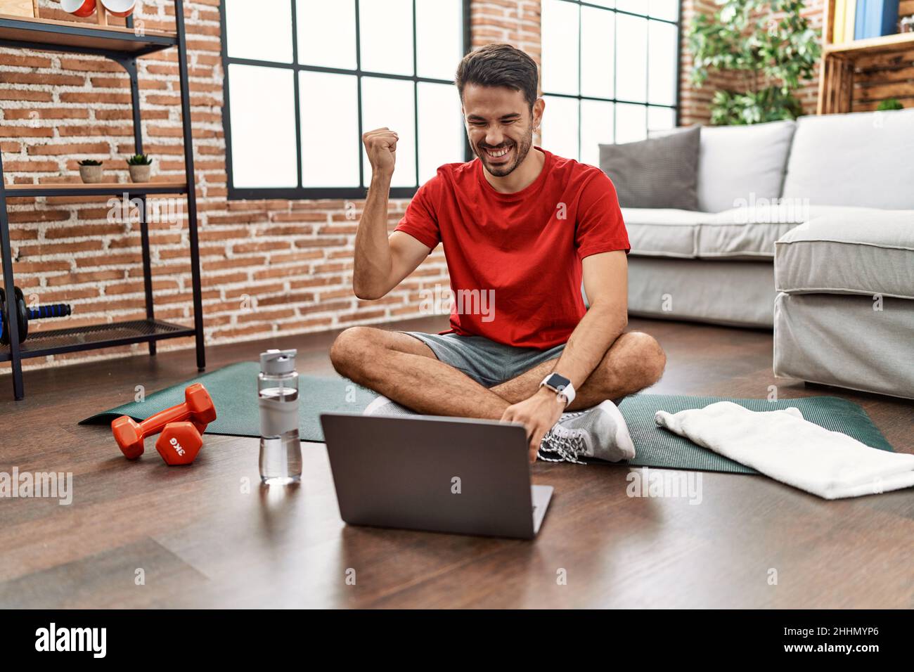 Young hispanic man watching training tutorial at home screaming proud ...