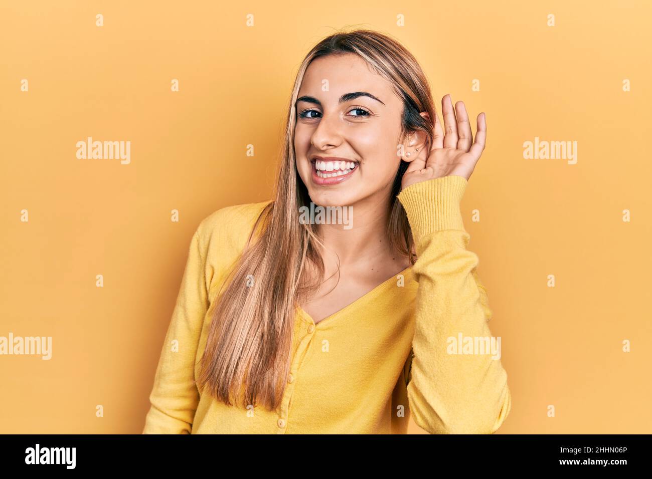Beautiful hispanic woman wearing casual yellow sweater smiling with ...