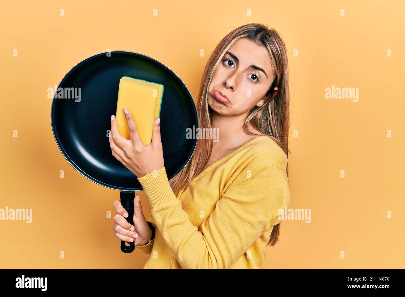 Beautiful hispanic woman cleaning cooking pan with scourer depressed ...