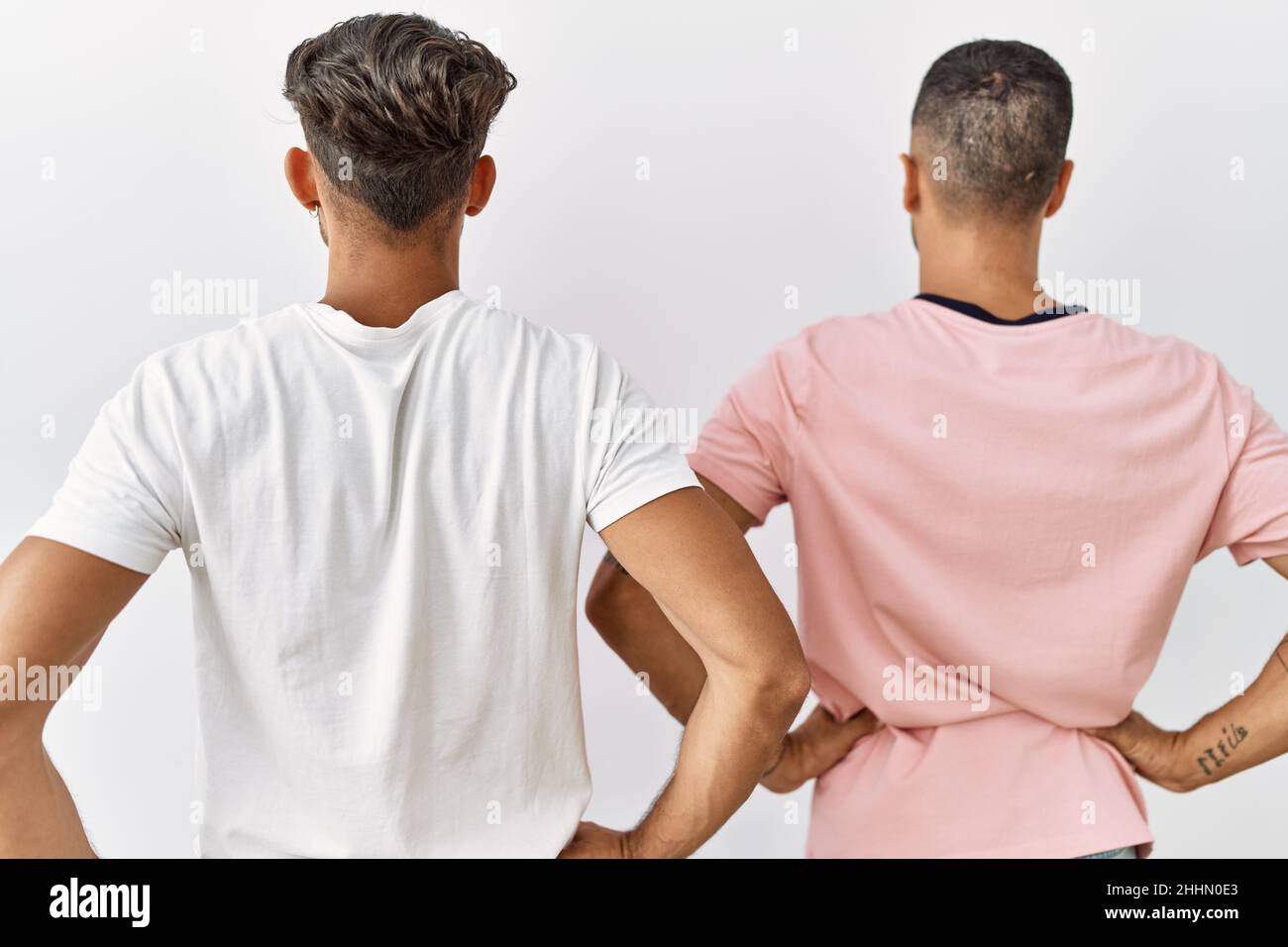 Young gay couple standing over isolated background standing backwards ...