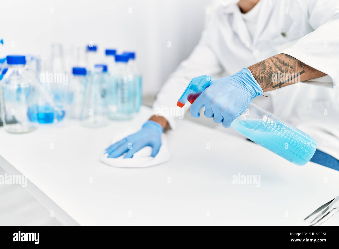 Handsome hispanic man working as scientific cleaning the table at ...