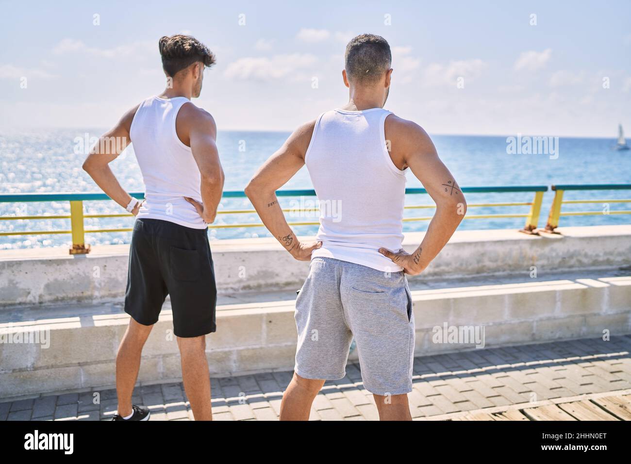 Two hispanic men sporty couple on back view looking sea standing at ...