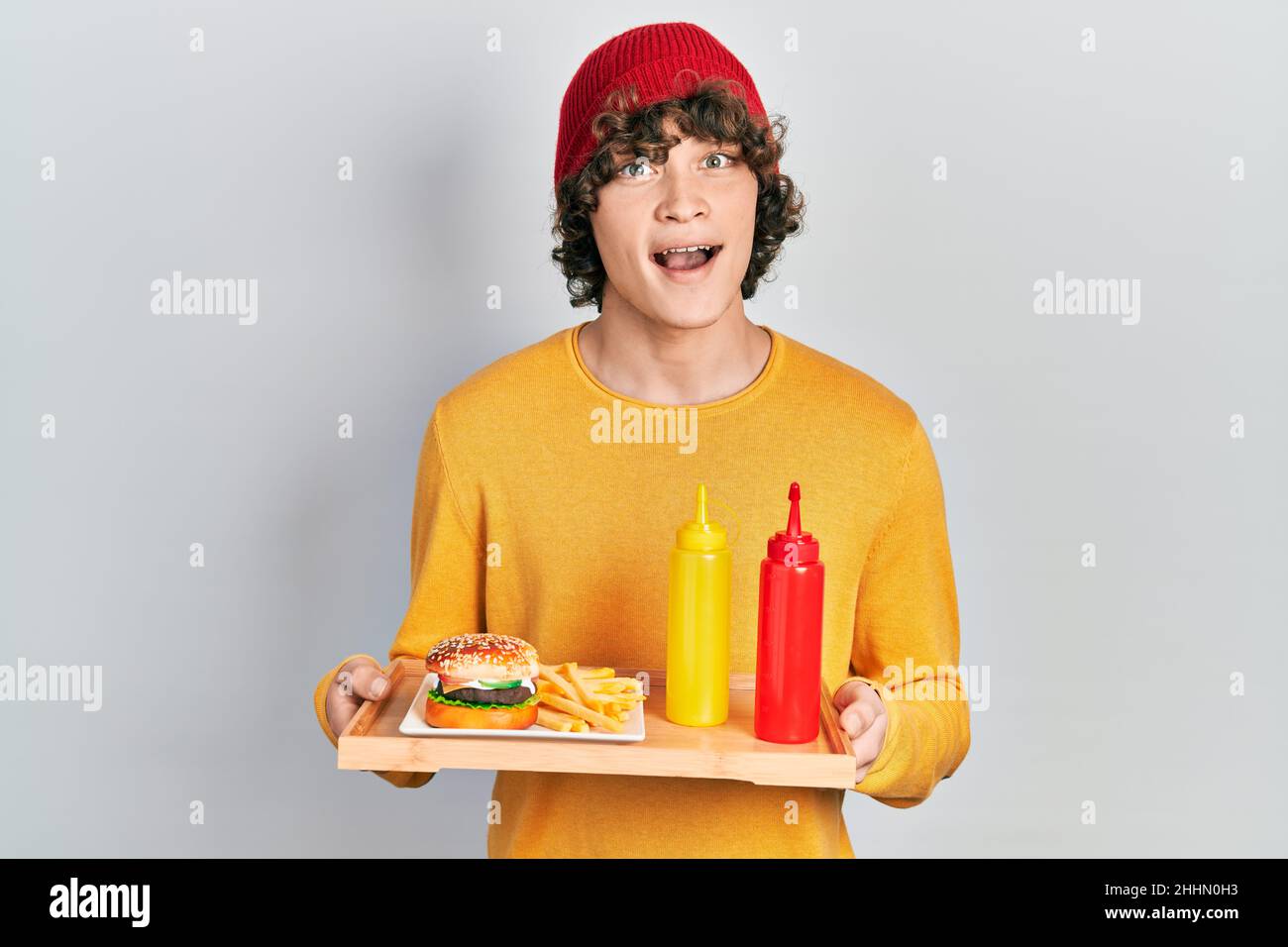 Handsome young man eating a tasty classic burger with ketchup and ...