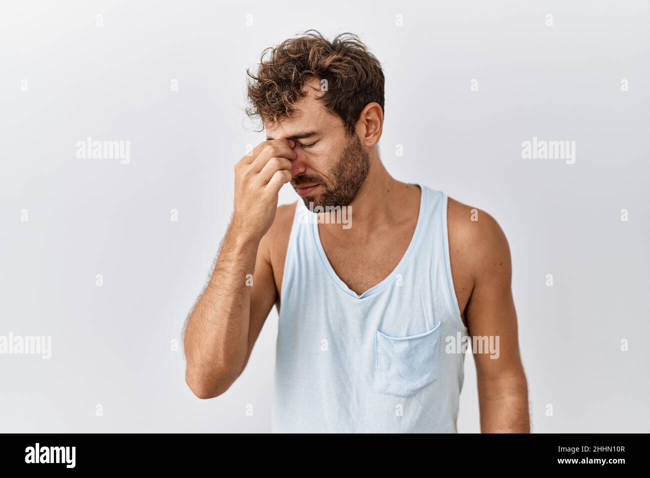 Young handsome man standing over isolated background tired rubbing nose ...