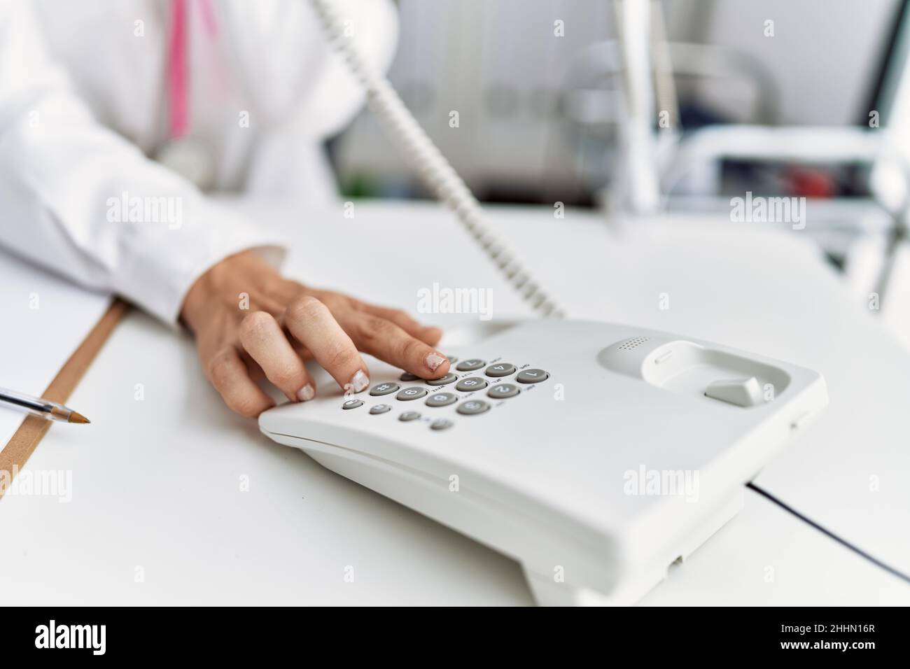 Young hispanic woman wearing doctor uniform talking on the telephone at ...