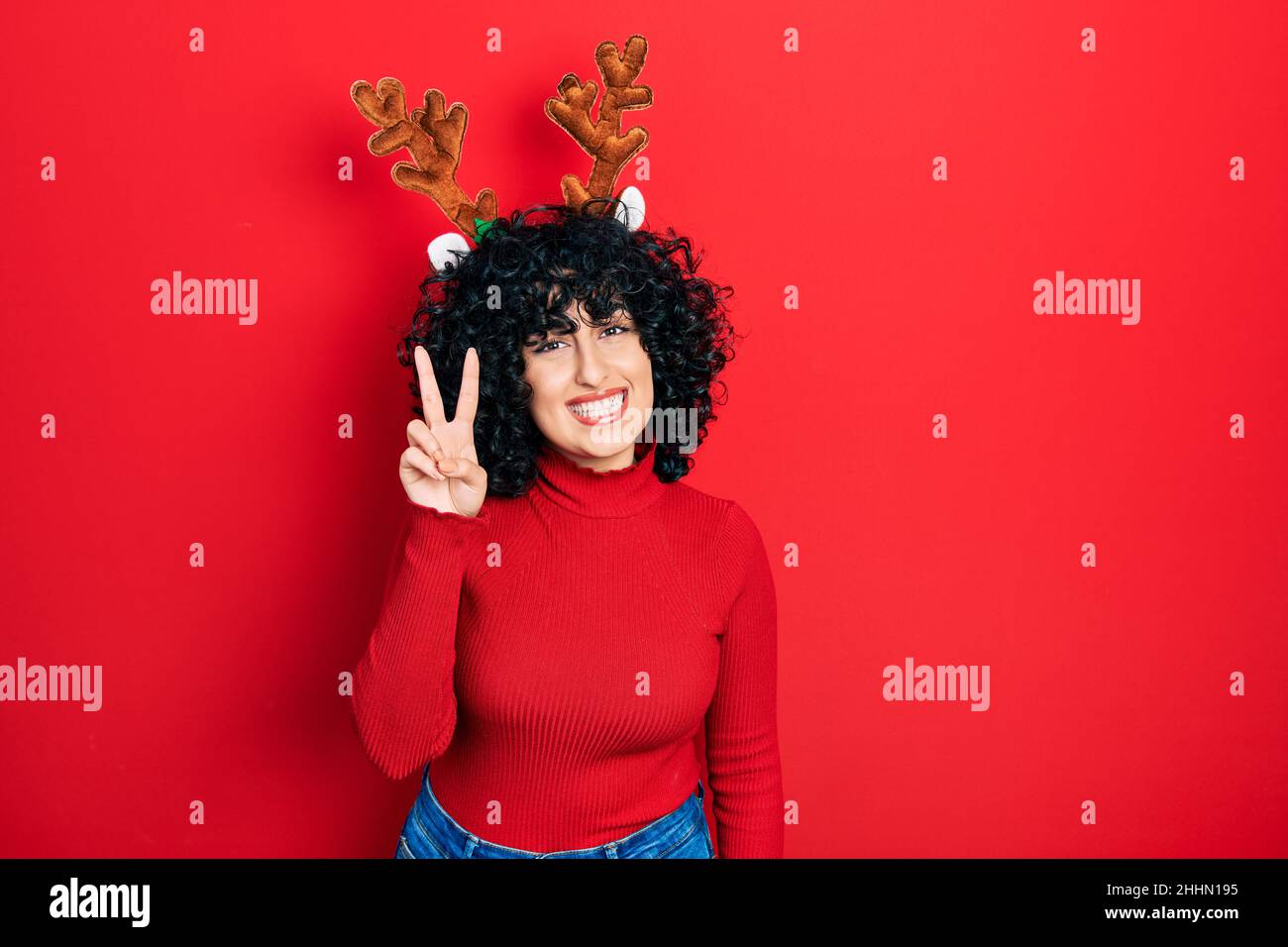 Young middle east woman wearing cute christmas reindeer horns smiling ...