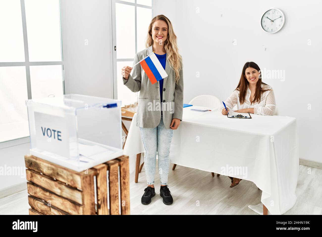 Young blonde woman at political stand holding russia flag looking ...