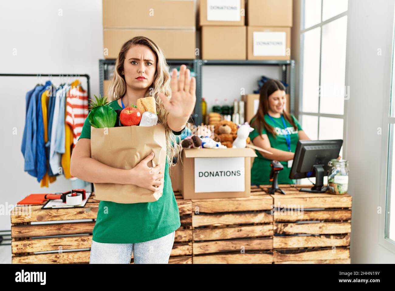Young blonde woman at volunteer center holding donations paper box with ...