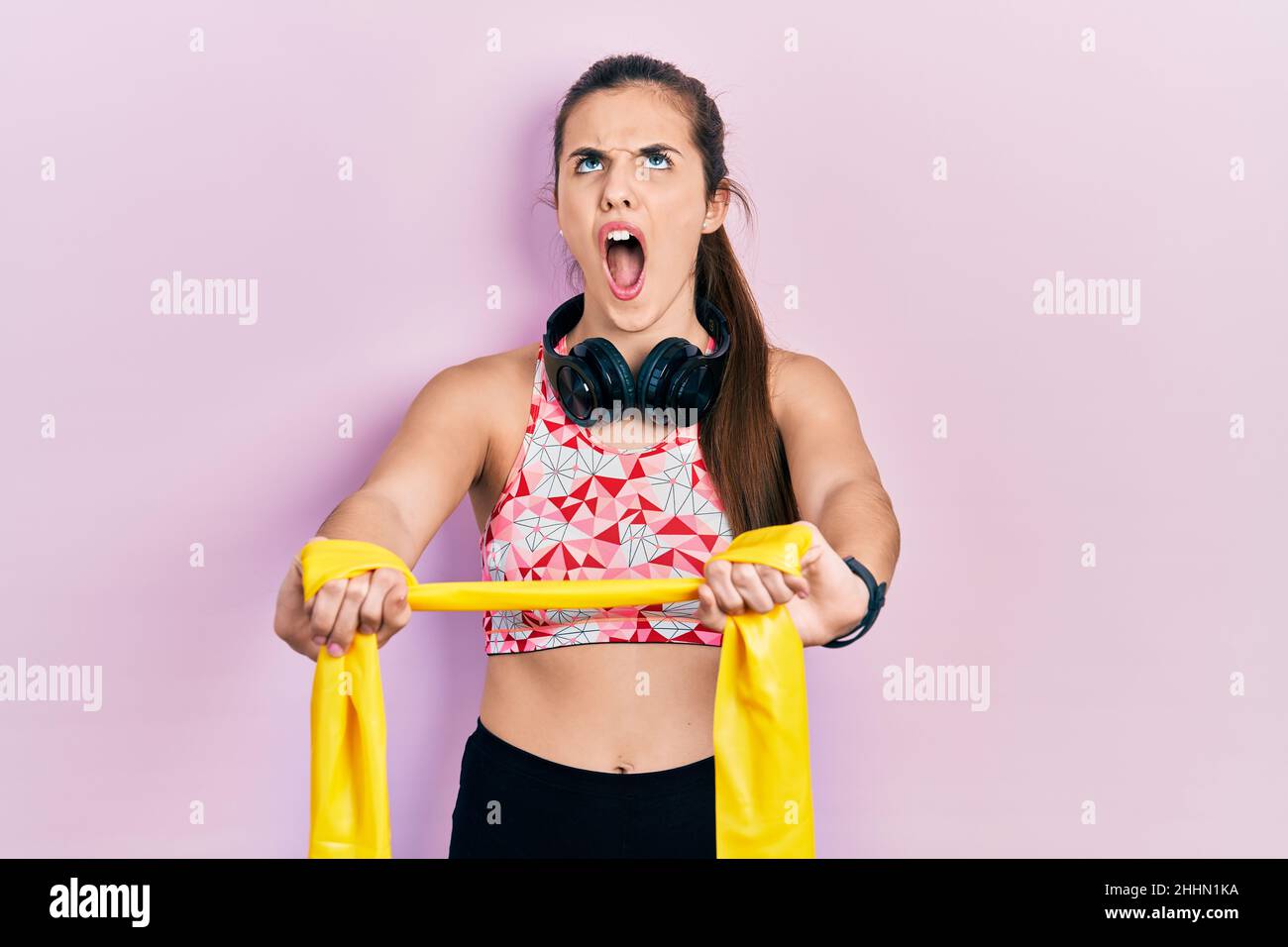 Young brunette teenager training arm resistance with elastic arm bands ...