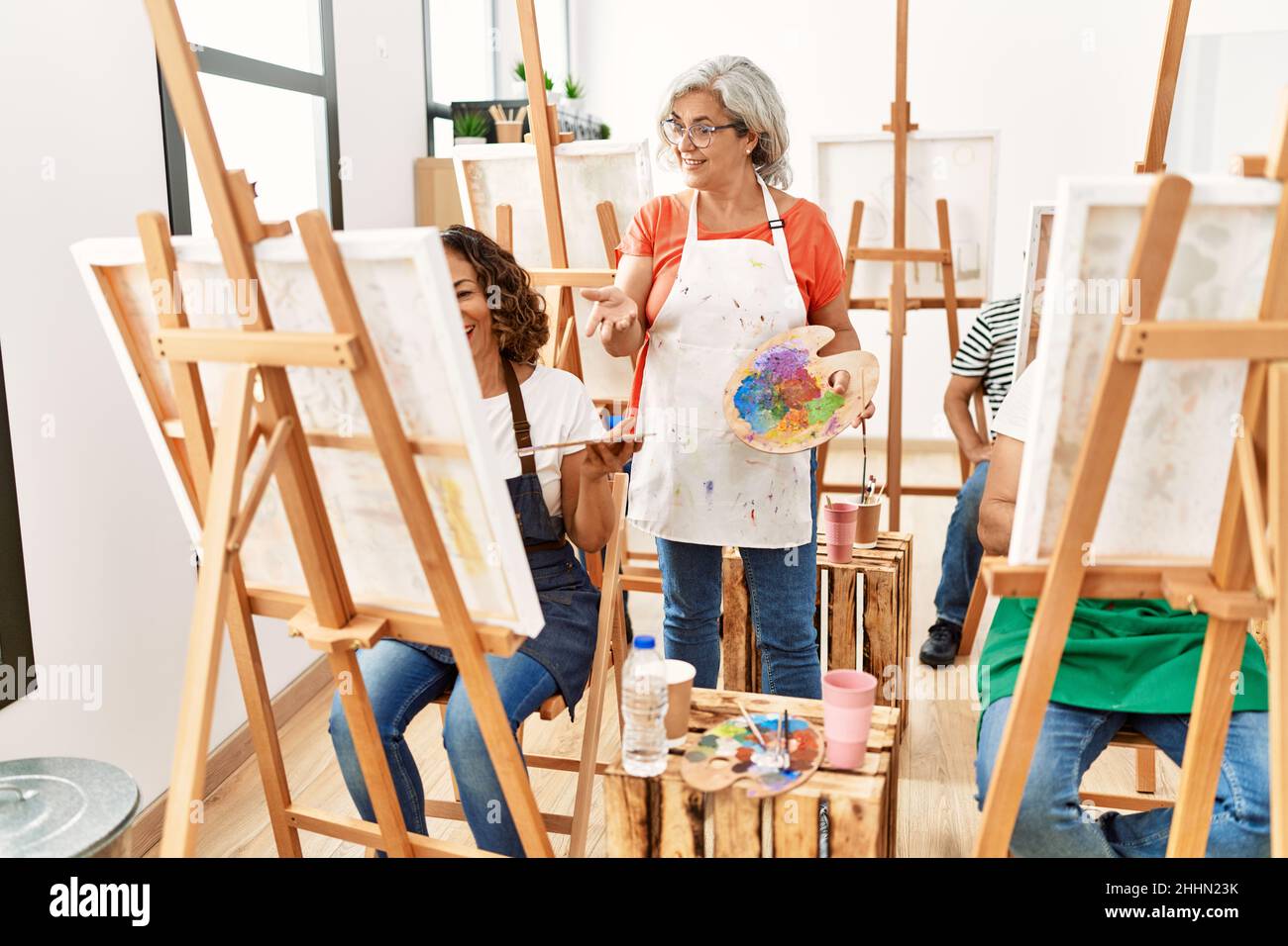 Group of middle age students drawing at art studio. Teacher looking ...