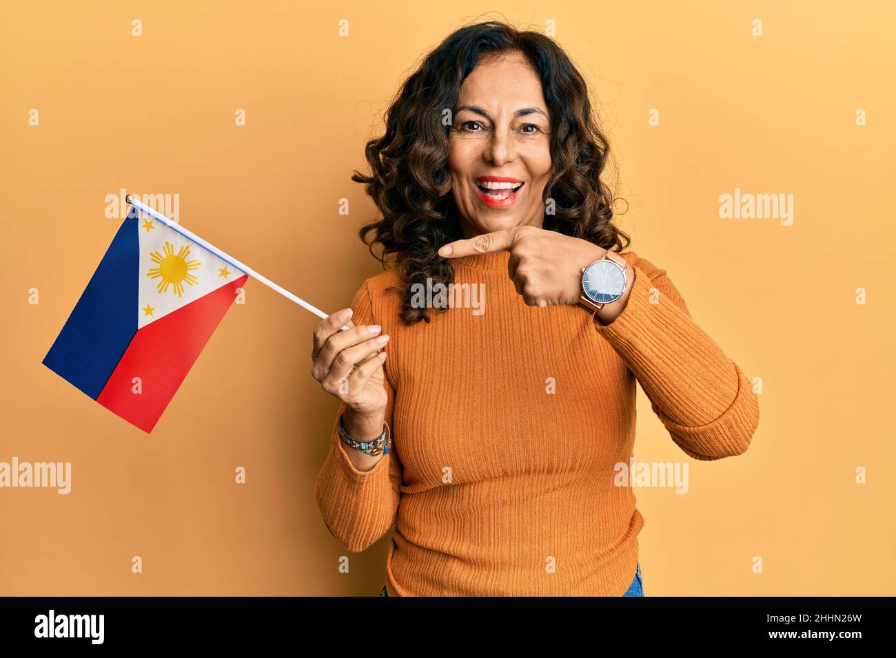 Middle age hispanic woman holding philippines flag smiling happy ...