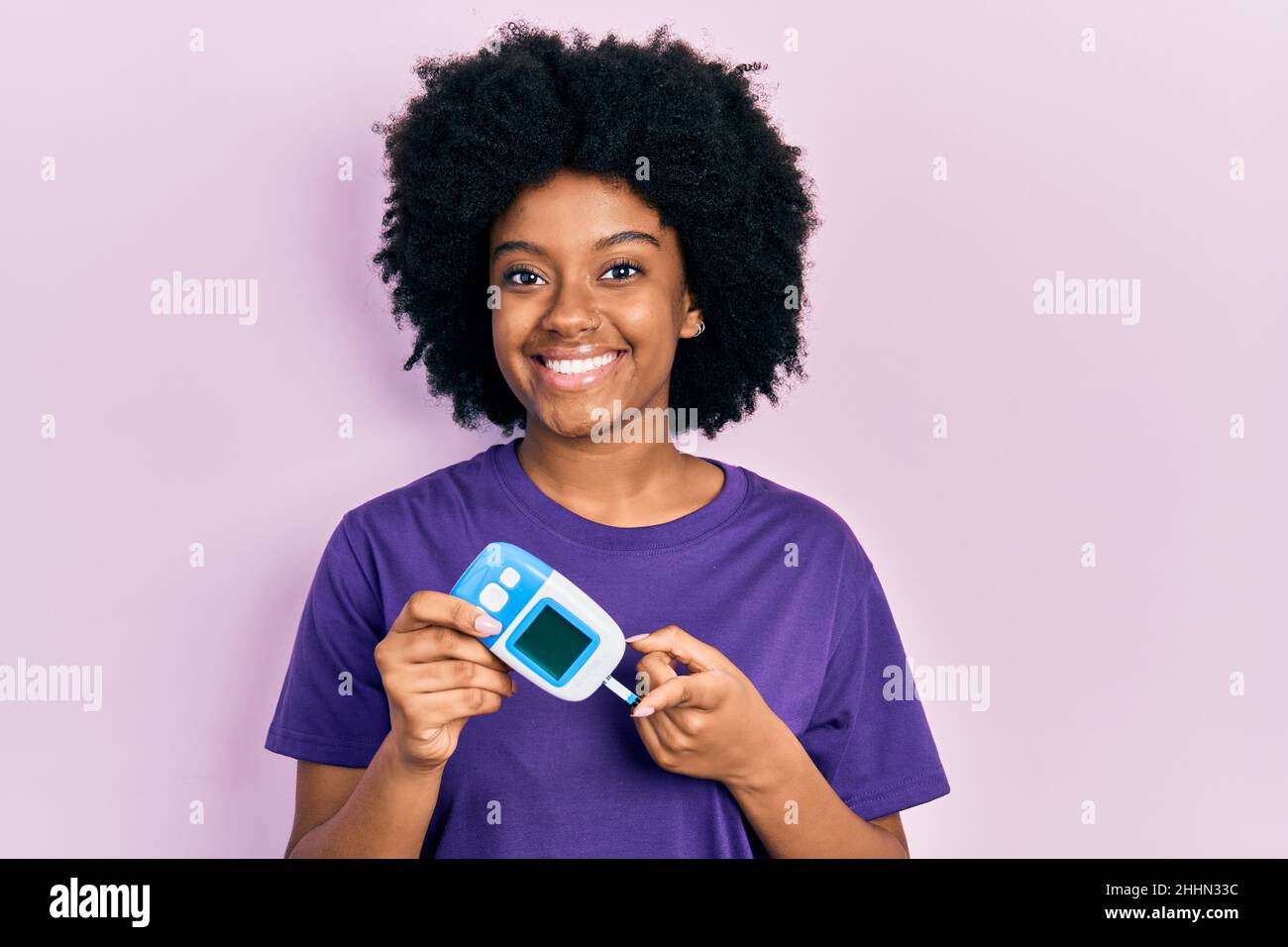 Young african american woman holding glucometer device smiling with a ...