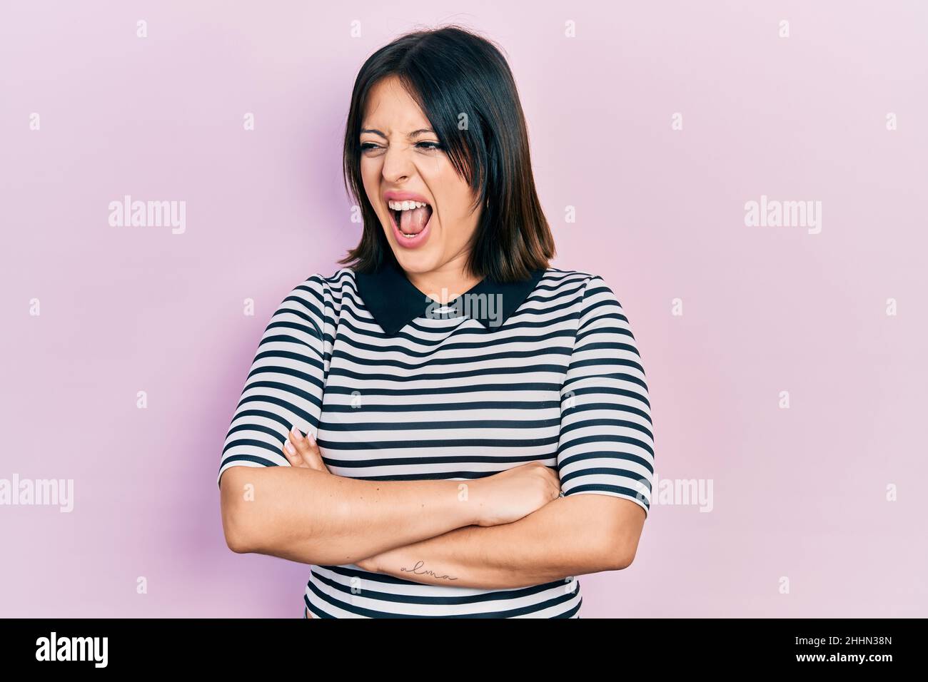 Young hispanic woman with arms crossed gesture angry and mad screaming ...