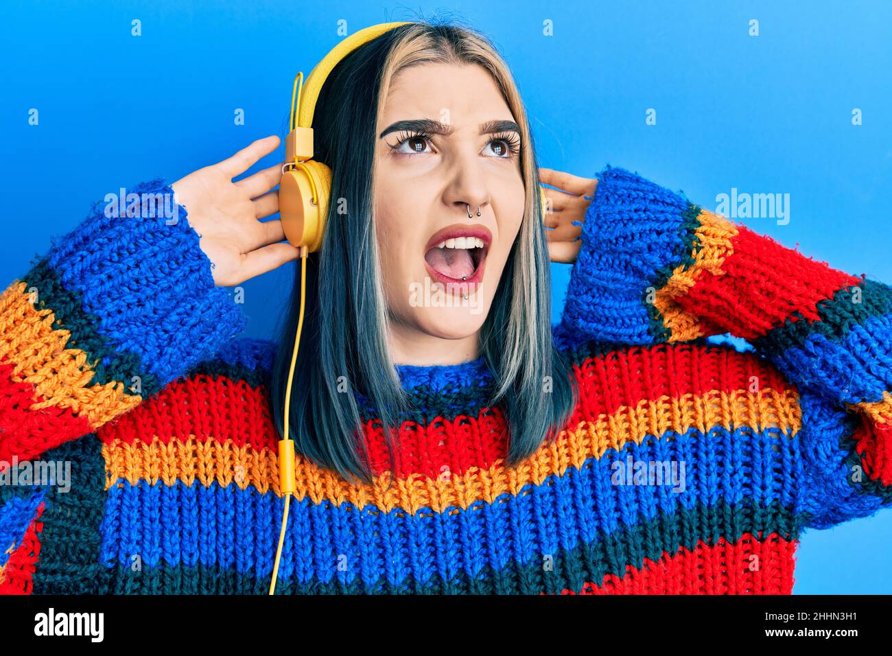 Young modern girl listening to music using headphones angry and mad ...