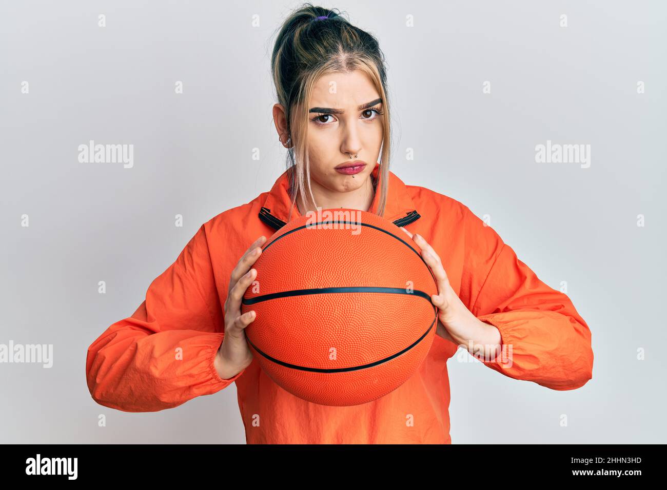 Young modern girl holding basketball ball depressed and worry for ...