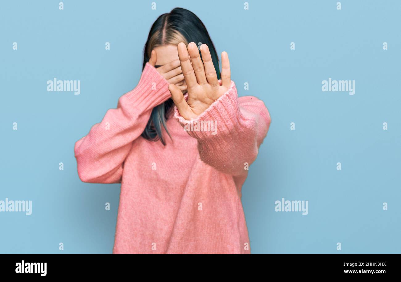 Young modern girl wearing pink wool winter sweater covering eyes with ...