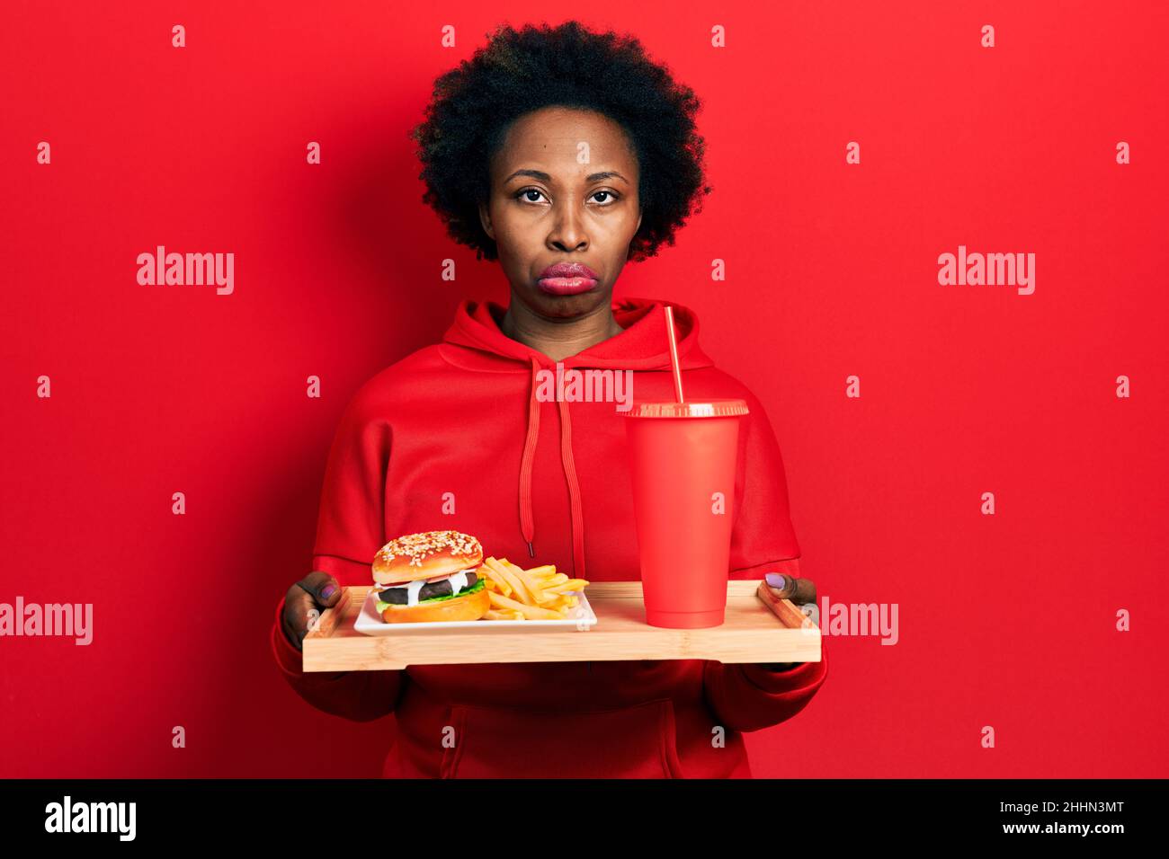 Young african american woman eating a tasty classic burger with fries ...