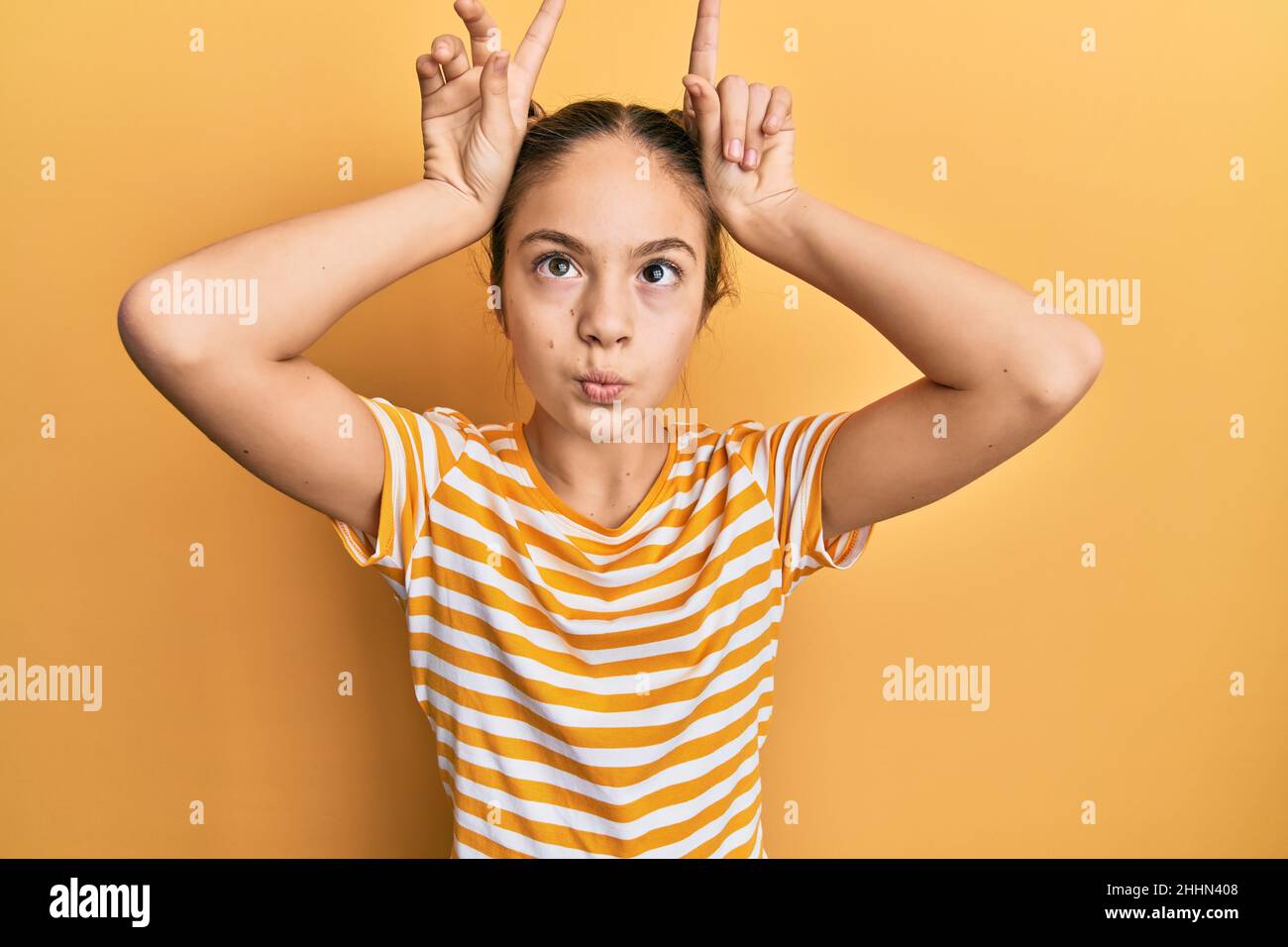 Beautiful brunette little girl wearing casual striped t shirt doing ...