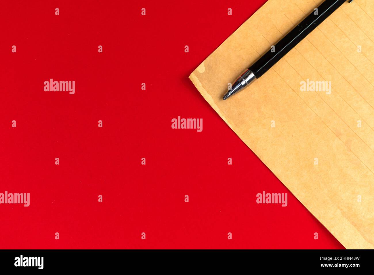 Vintage letter paper with black pencil on a bright red table background ...