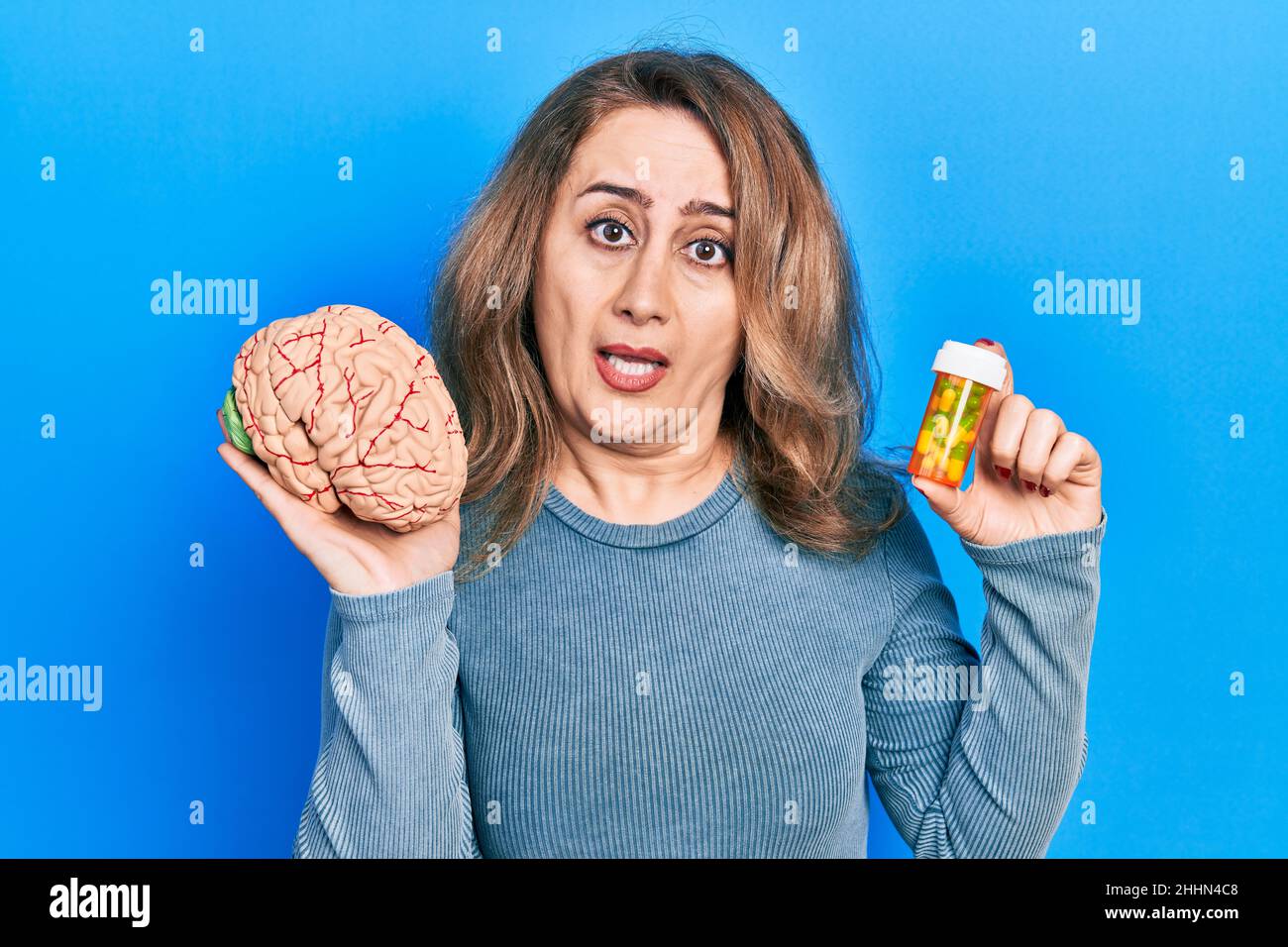 Middle age caucasian woman holding brain and pills as mental health ...