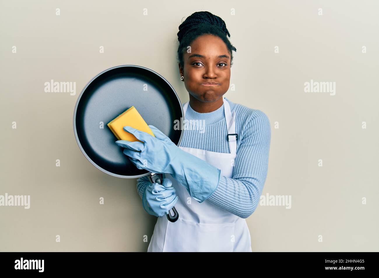 African american woman with braided hair wearing apron holding scourer ...