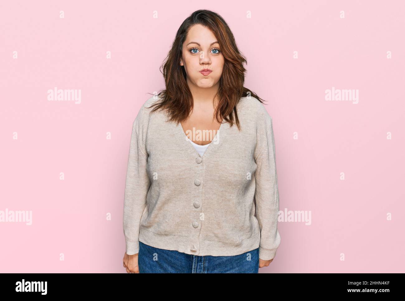 Young plus size woman wearing casual clothes puffing cheeks with funny ...