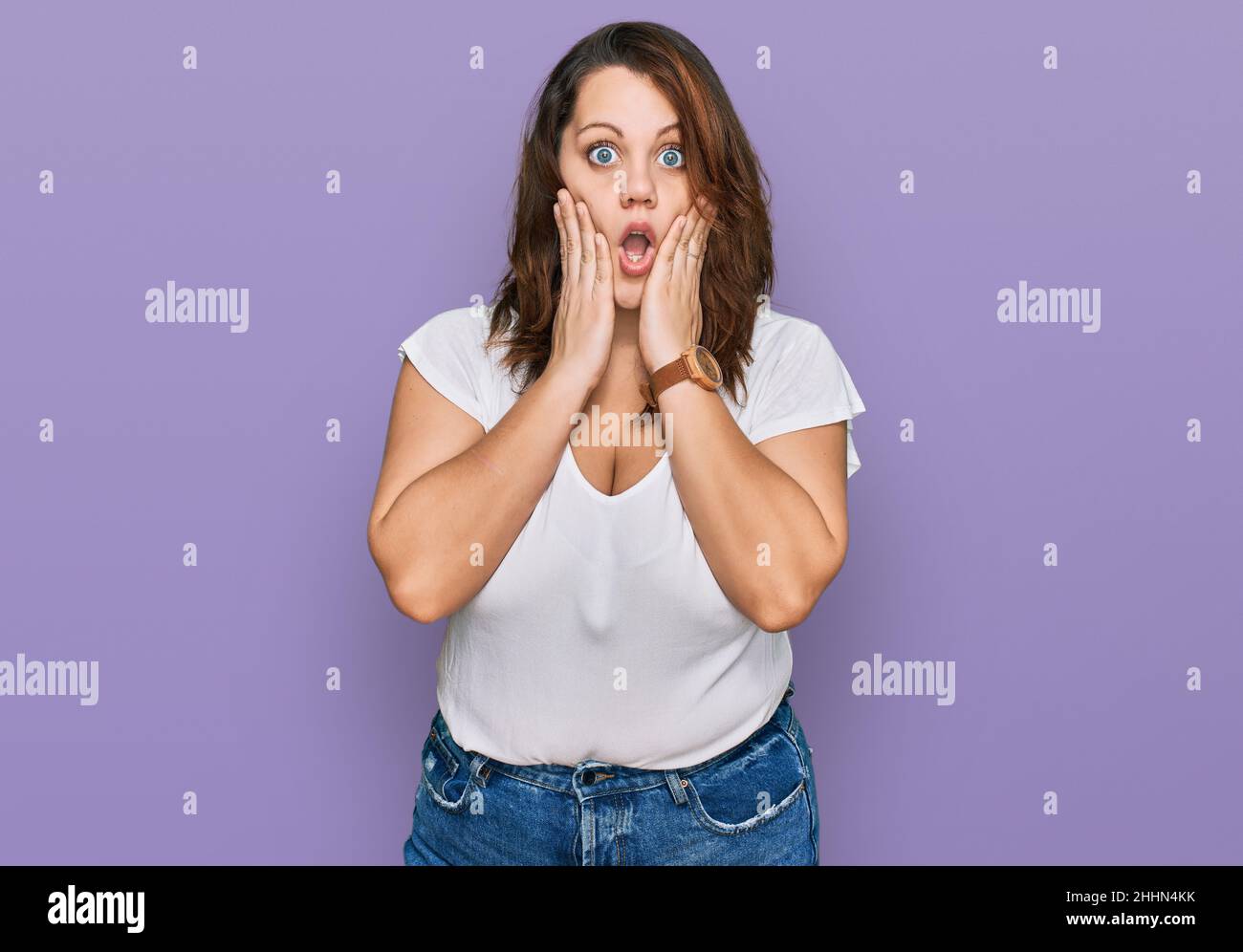Young plus size woman wearing casual white t shirt afraid and shocked ...