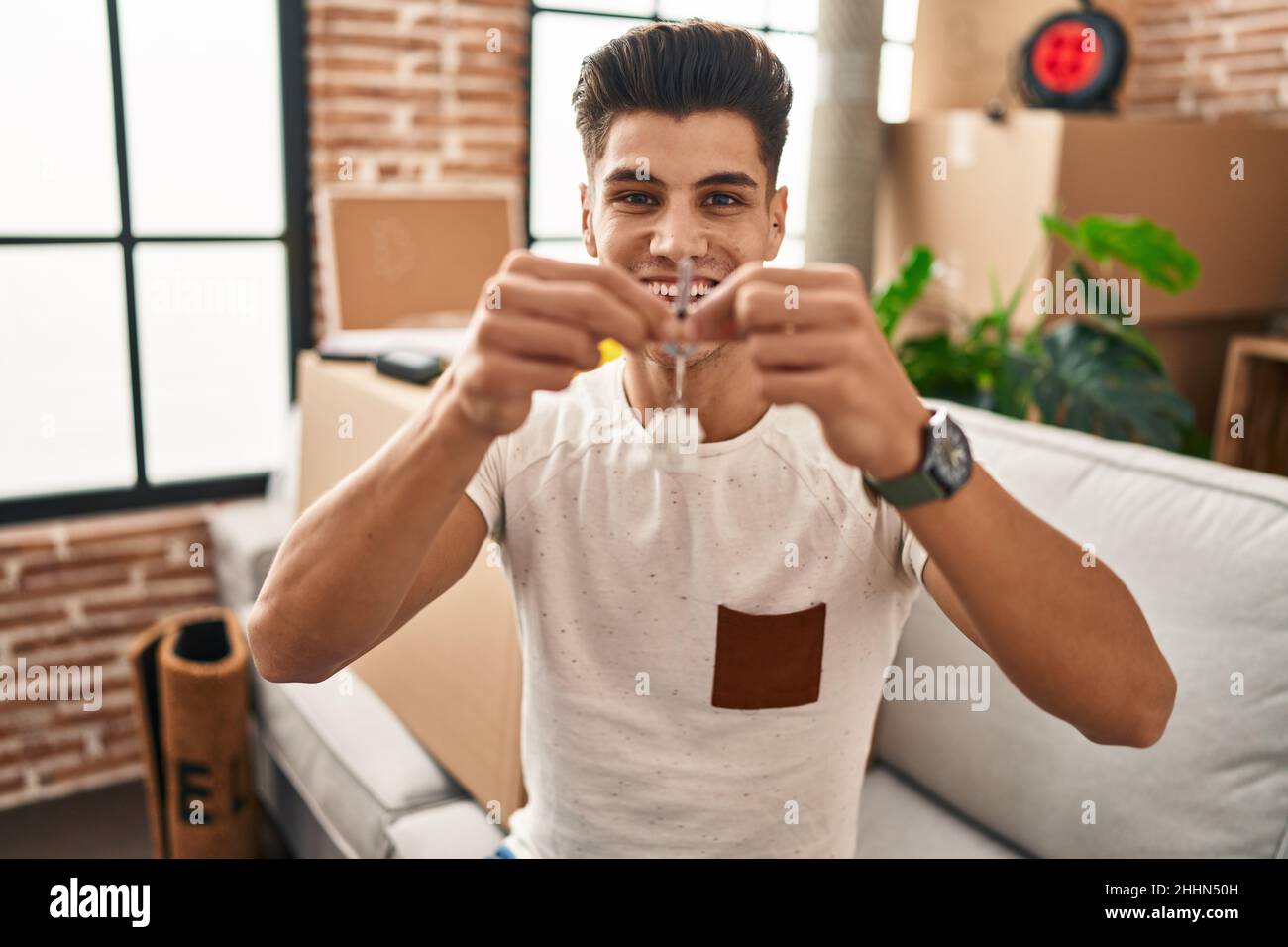Young hispanic man smiling confident holding key of house at new home ...
