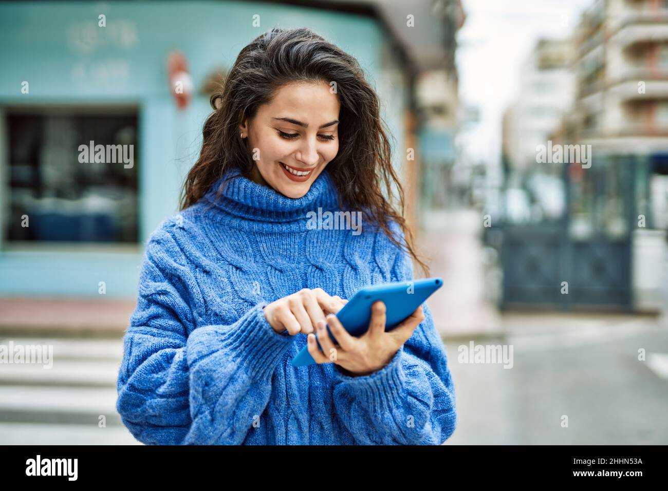 Young hispanic woman smiling happy using touchpad at the city Stock ...