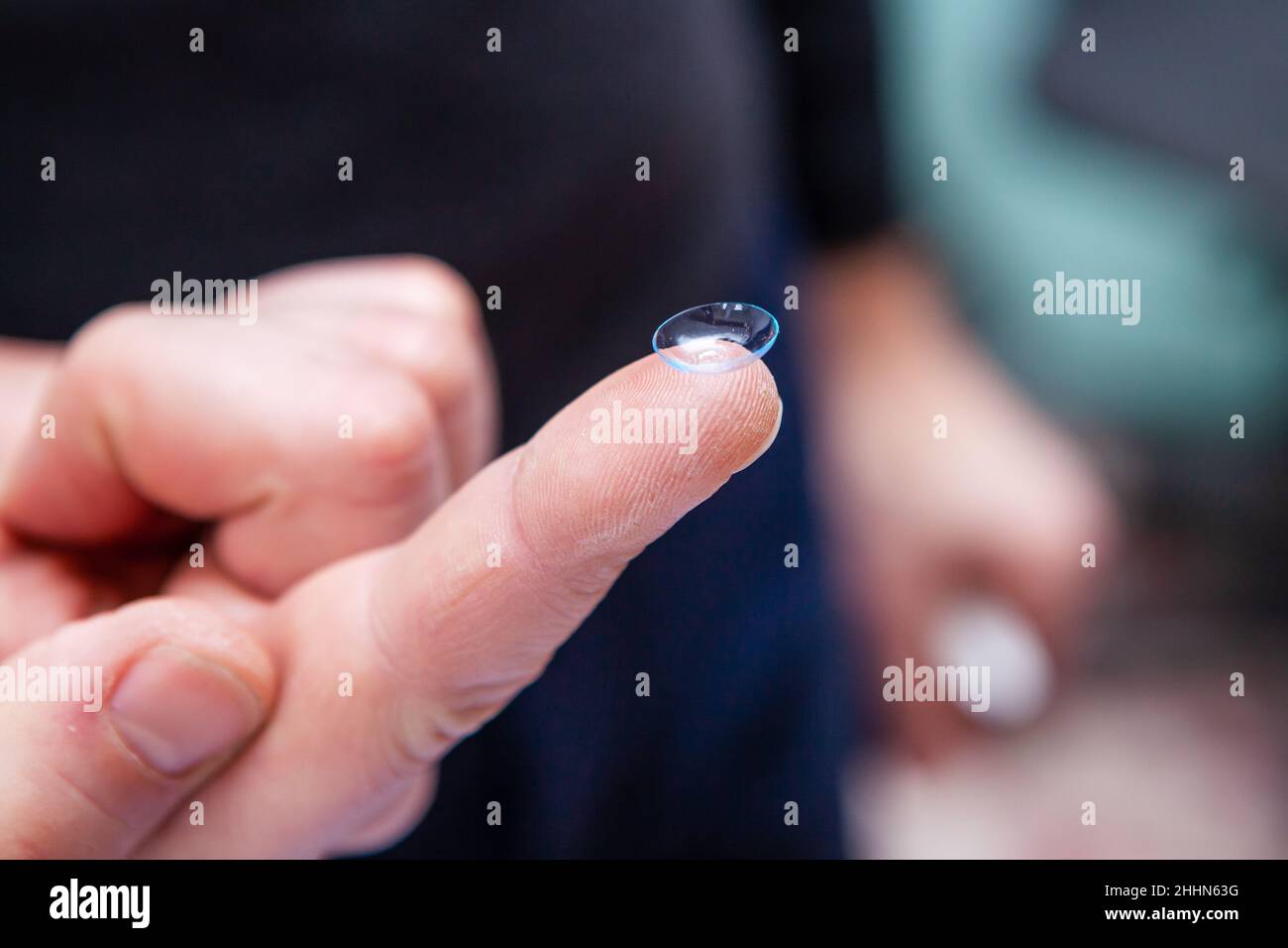 An optician doctor shows a clear and clean contact lens resting on a ...