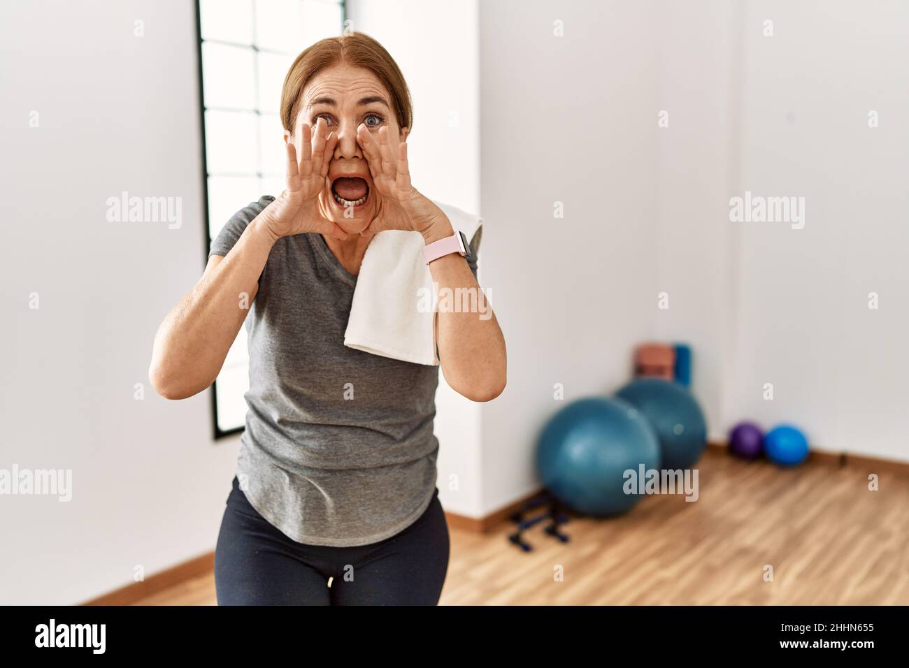 Middle age woman wearing sporty look training at the gym room shouting ...