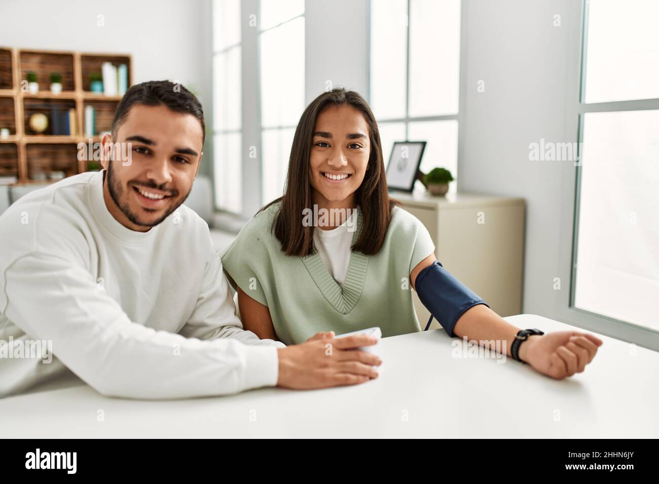 Young latin couple smiling happy measuring blood pressure using ...