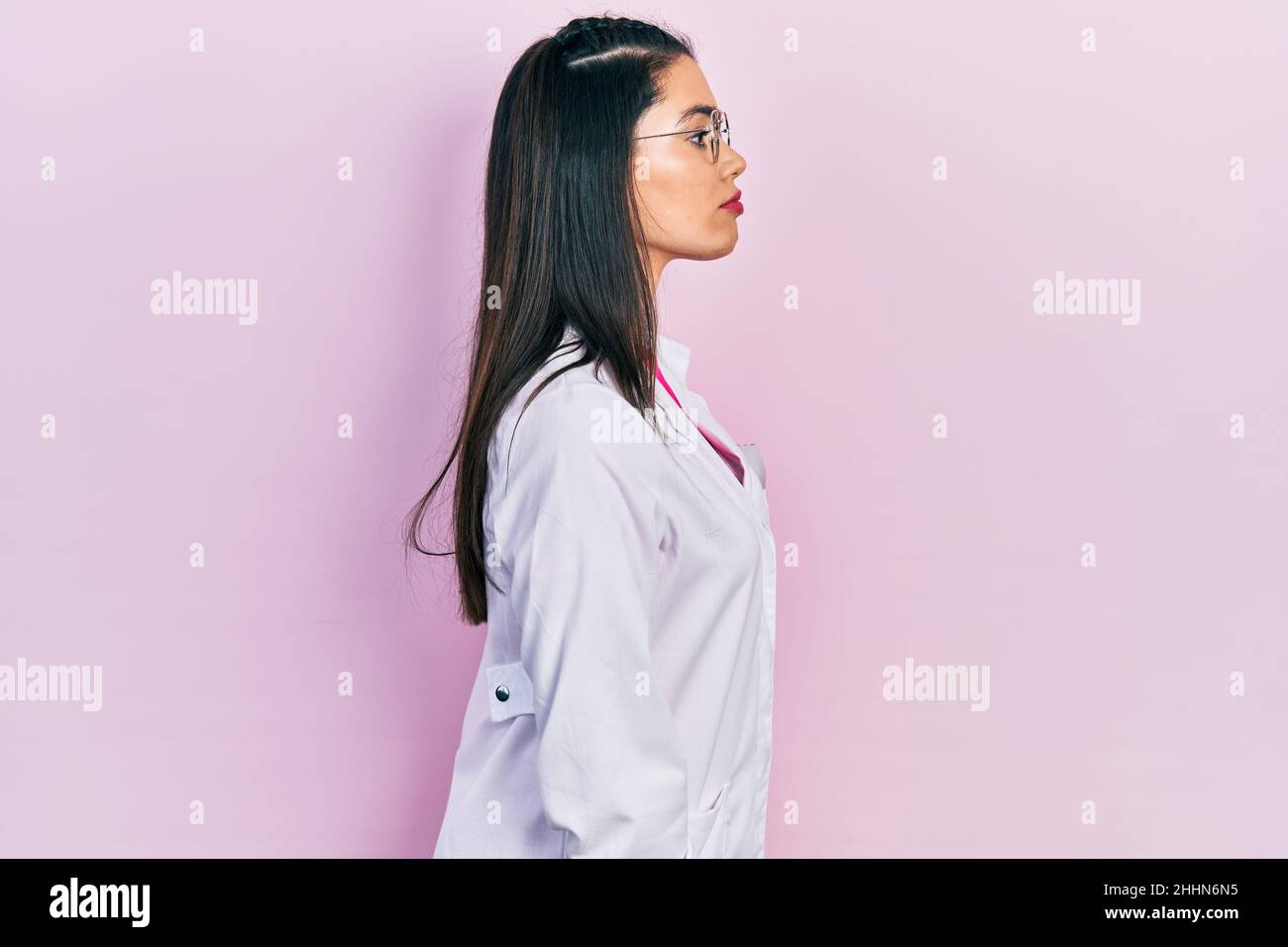 Young hispanic girl wearing scientist uniform looking to side, relax ...