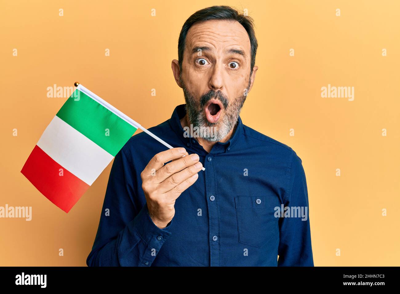 Middle age hispanic man holding italy flag scared and amazed with open ...