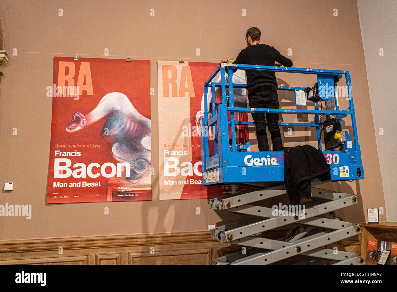 LONDON, UK. 25 Jan, 2022. A worker standing on a ladder places posters ...