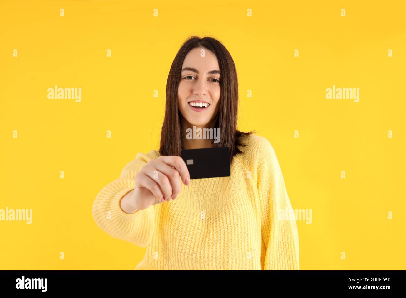 Young attractive girl with card on yellow background Stock Photo - Alamy