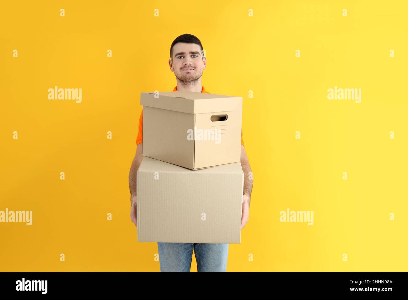 Delivery guy hold boxes on yellow background Stock Photo - Alamy