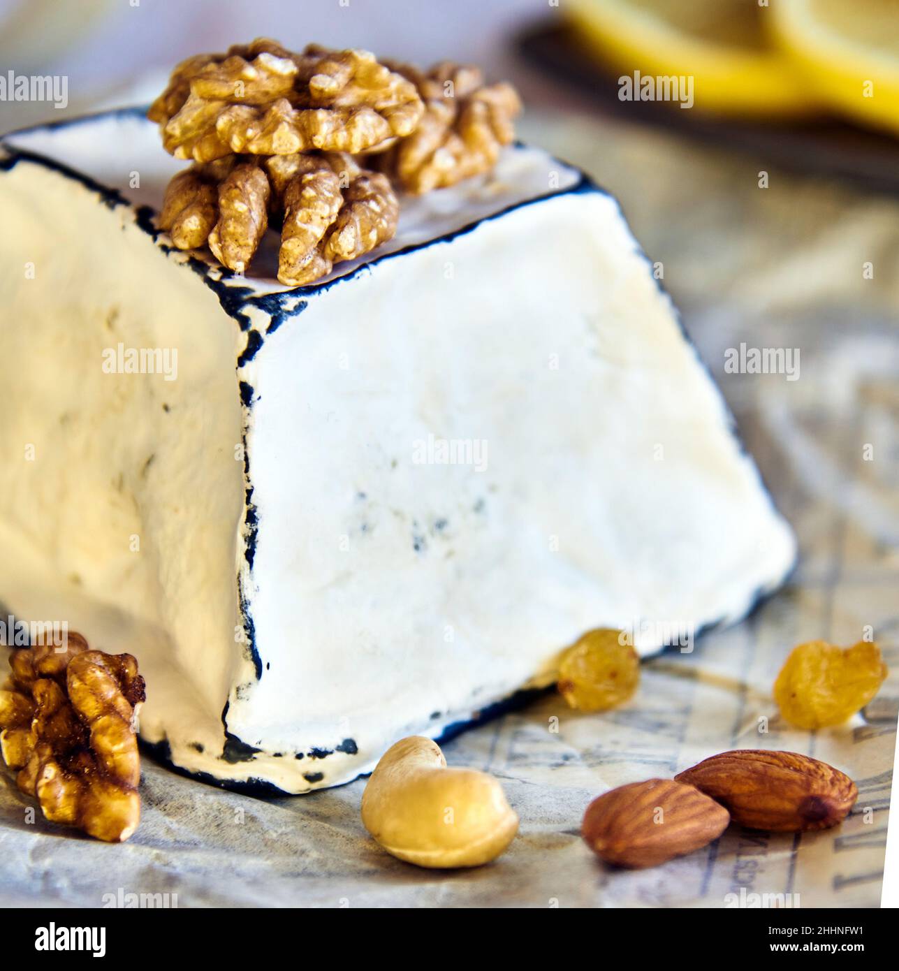 Cheese in white mold with black charcoal edges, nuts and raisins, on ...