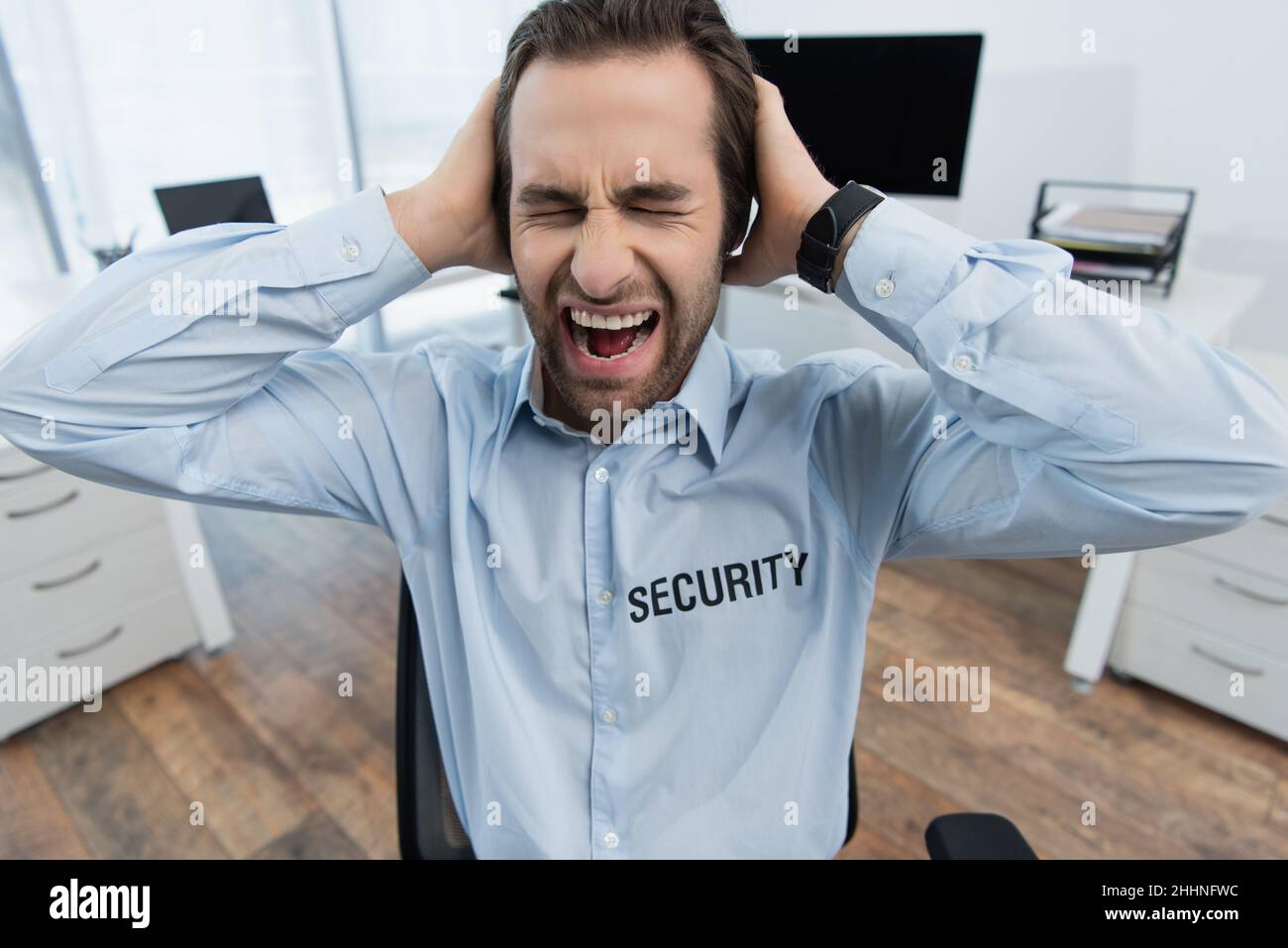 shocked security man with closed eyes holding hands on head and ...