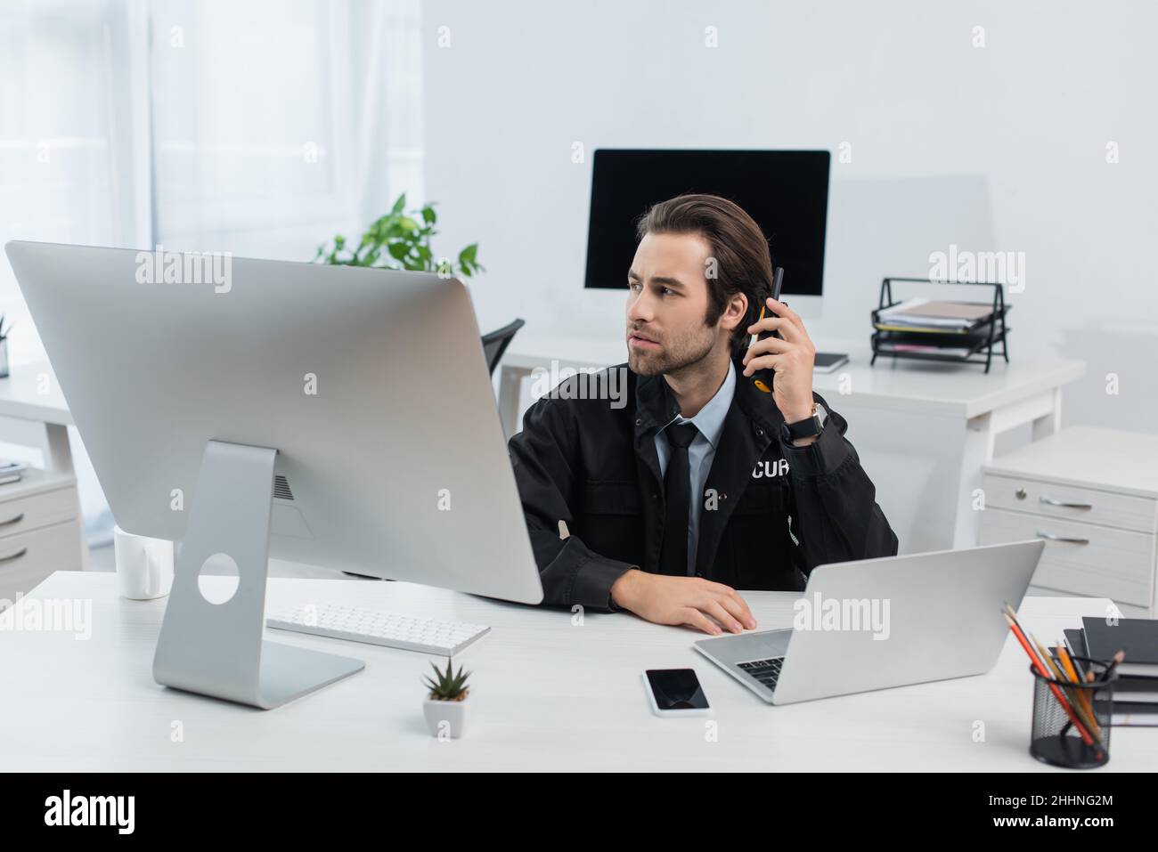 security man calling on walkie-talkie near computers in surveillance ...