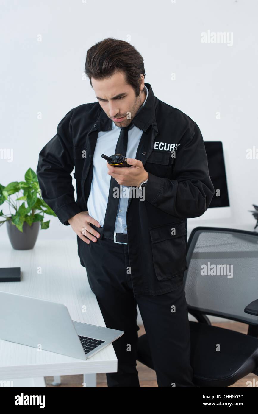 security man in black uniform calling on walkie-talkie while standing ...