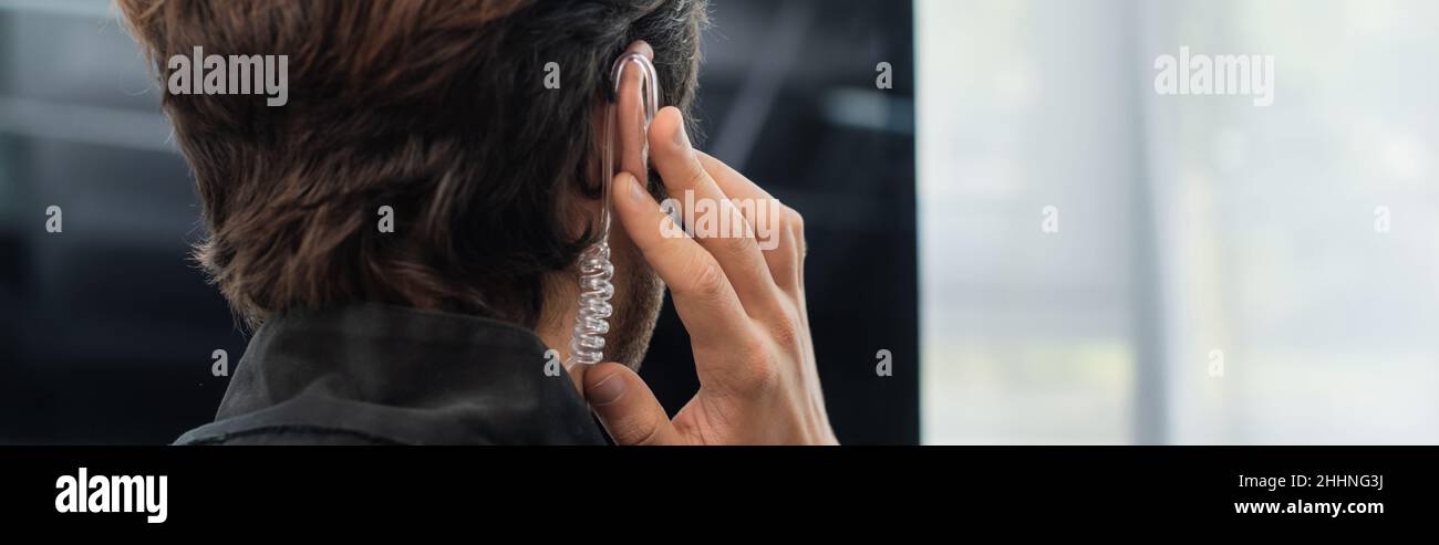 back view of security man adjusting earphone, banner Stock Photo - Alamy