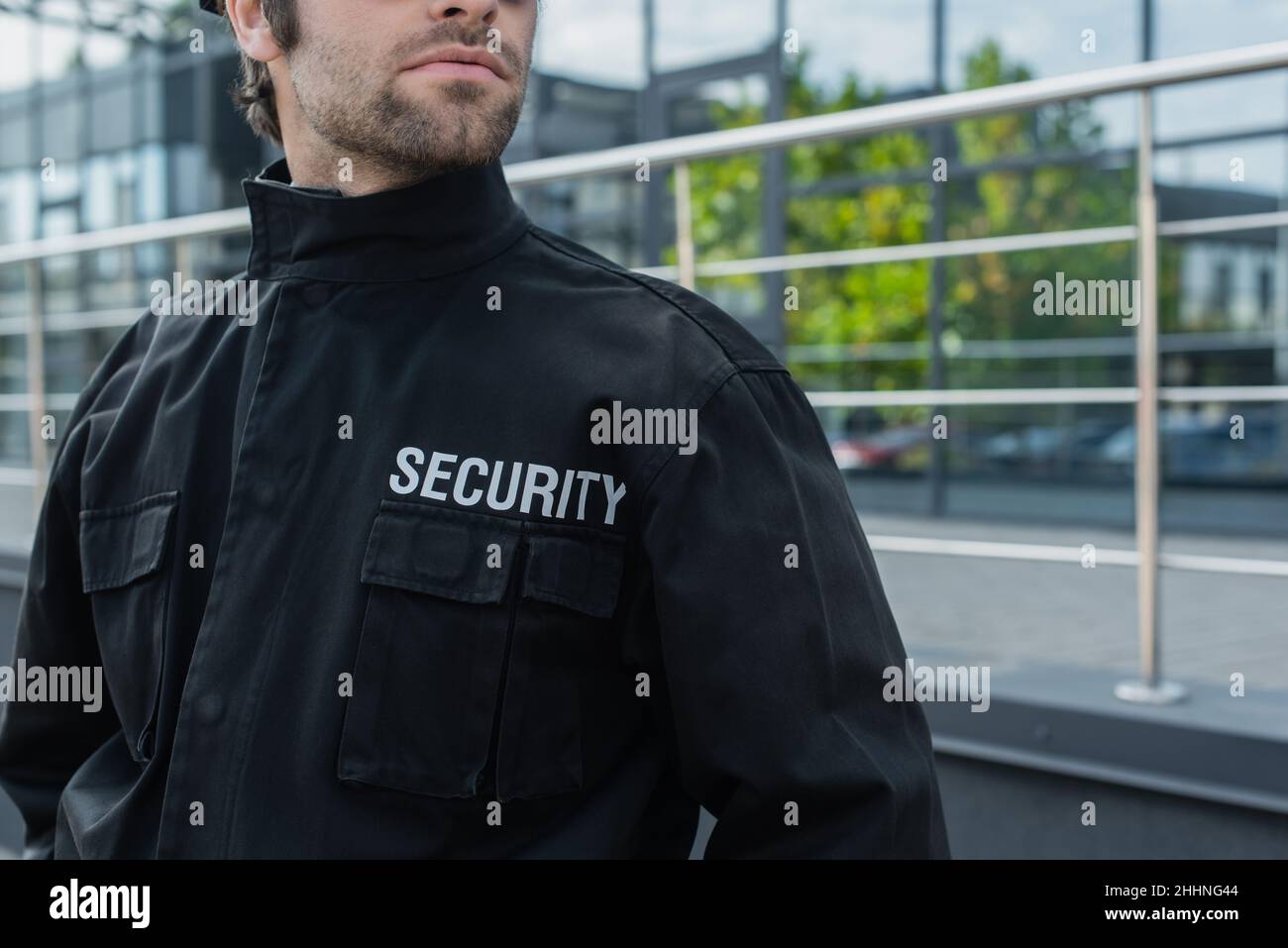 partial view of guard in black uniform with security lettering near ...